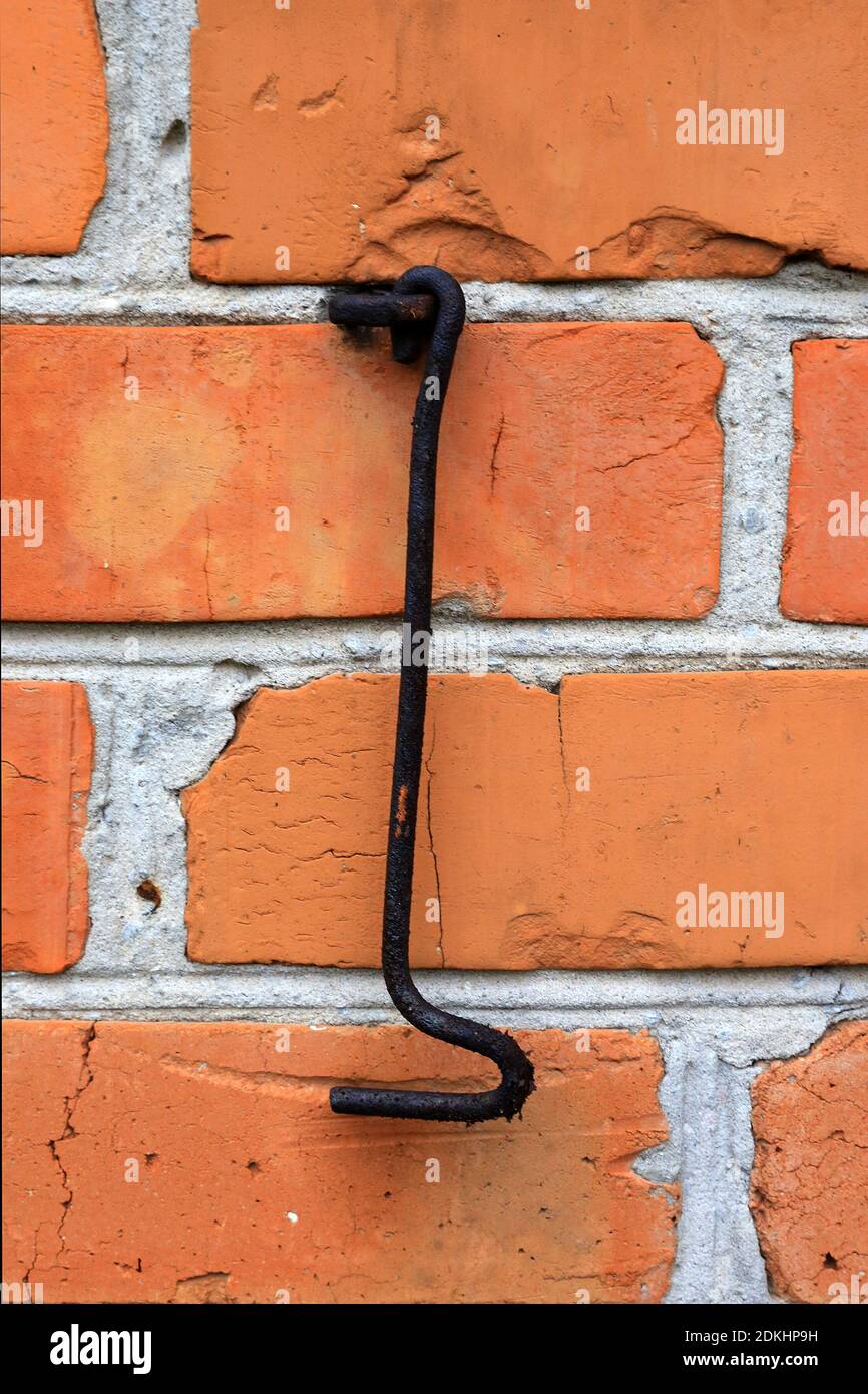 old rusty metal hook on red brickwork wall background Stock Photo - Alamy