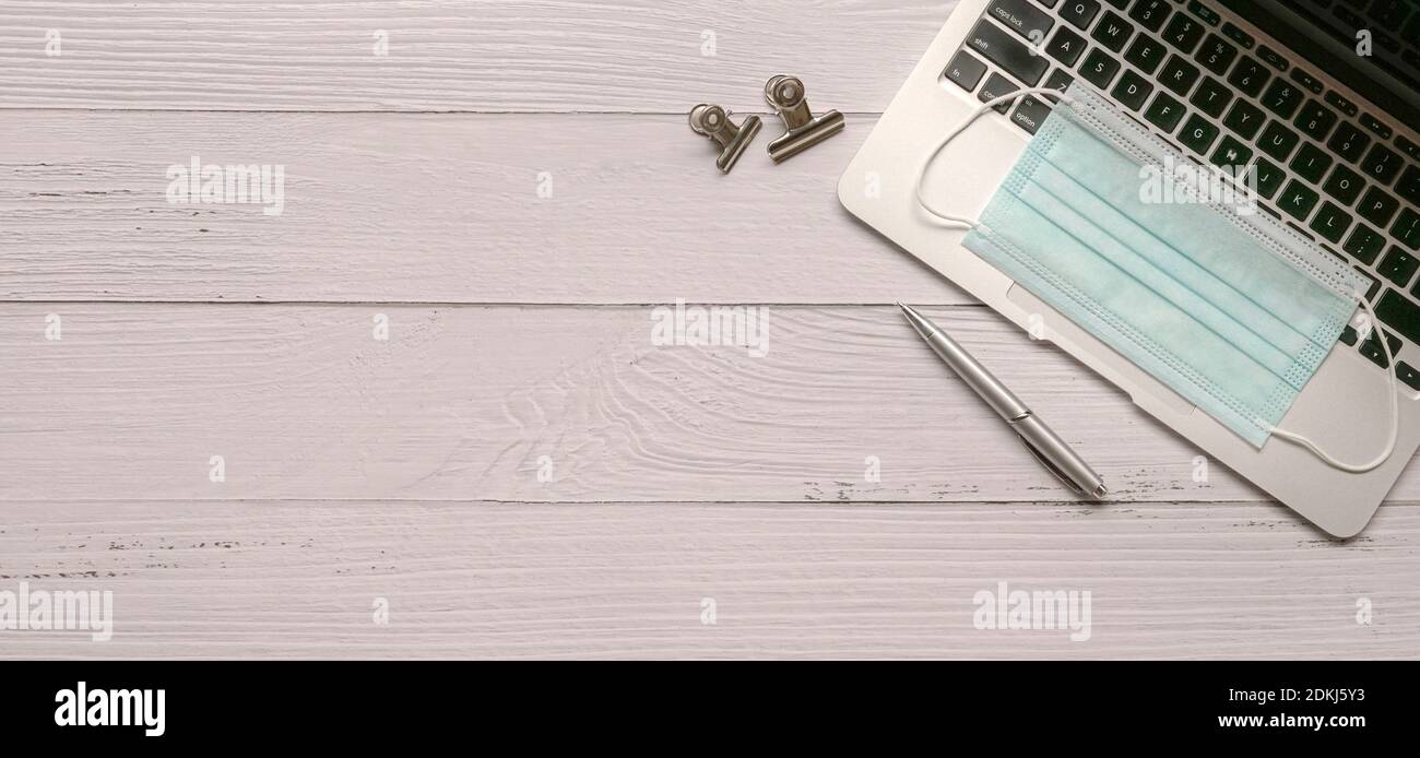 Wood office desk table with laptop, face mask and supplies. Copy space ...