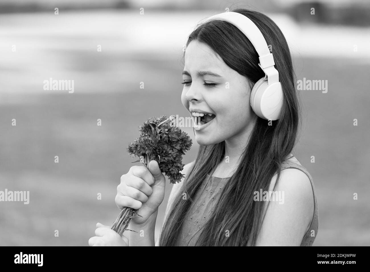 Kiddie song. Happy kid sing song outdoors. Using flowers as microphone ...