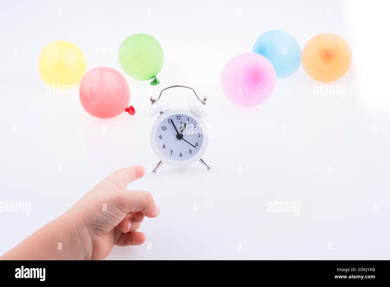 Cropped Hand Pointing Towards Clock And Colorful Balloons Over White ...