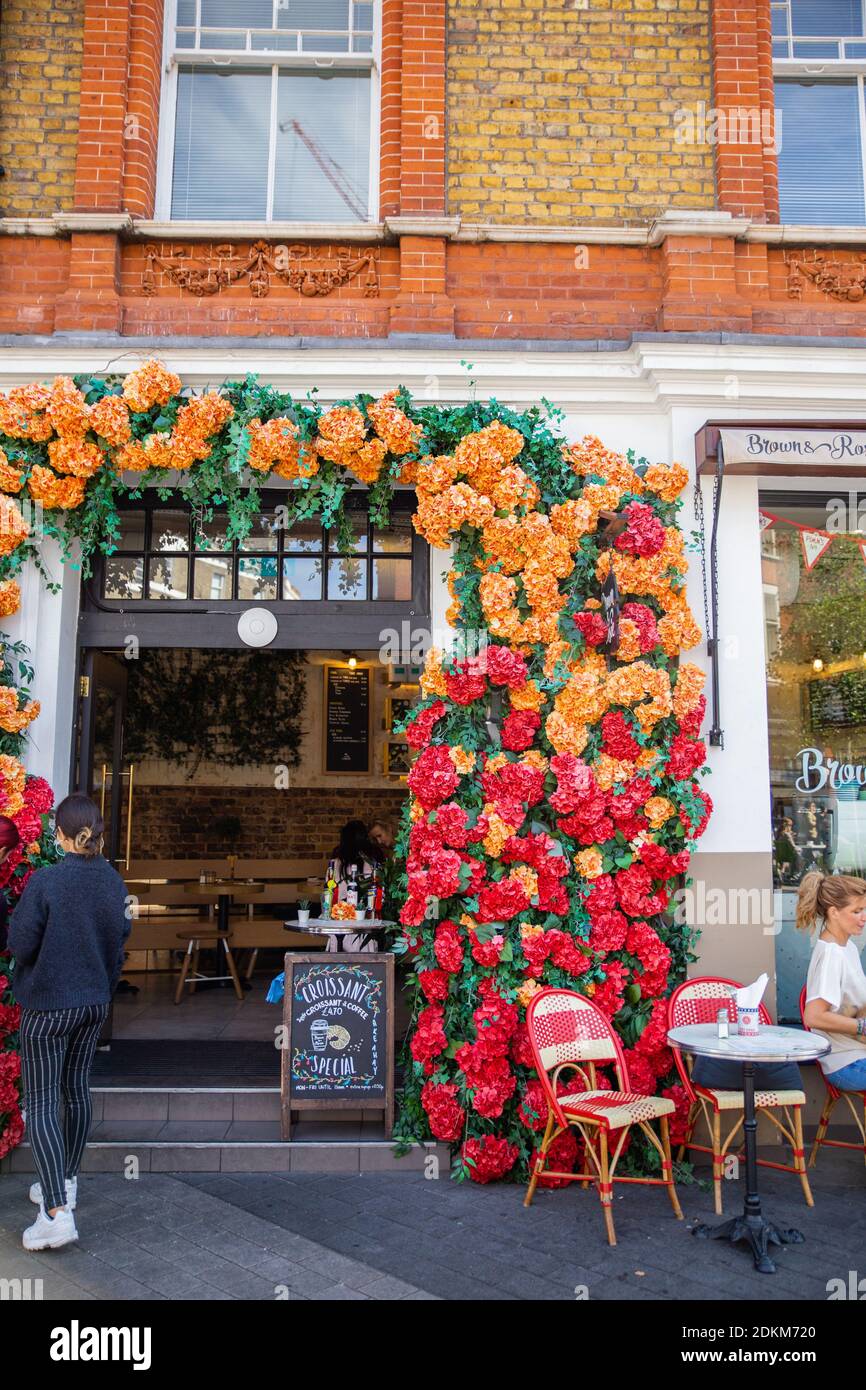 British cafe with an arch of red and orange flowers above the entrance ...