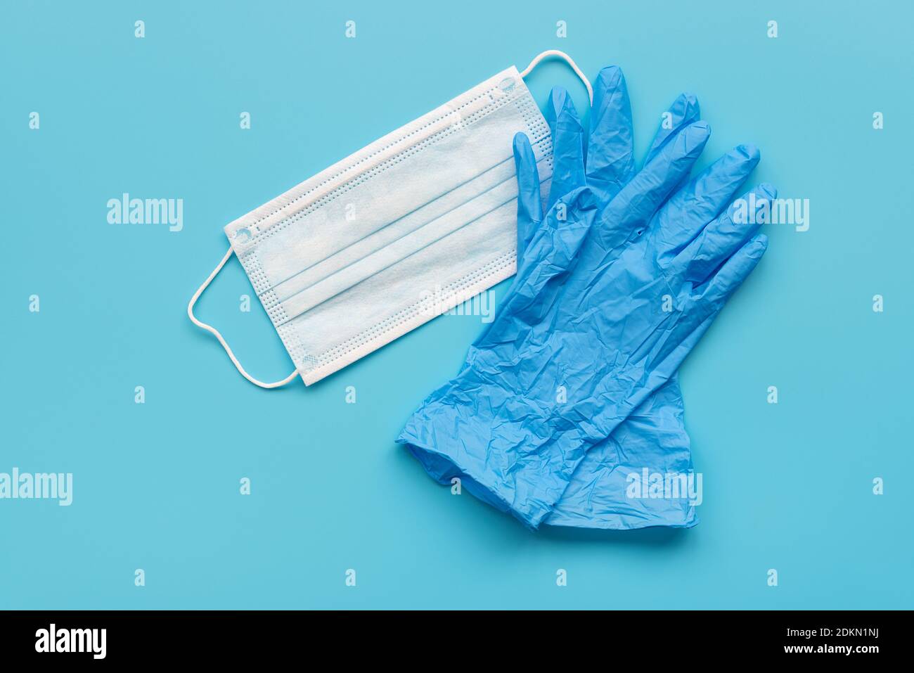 Pair of latex medical gloves and surgical ear-loop mask on blue ...