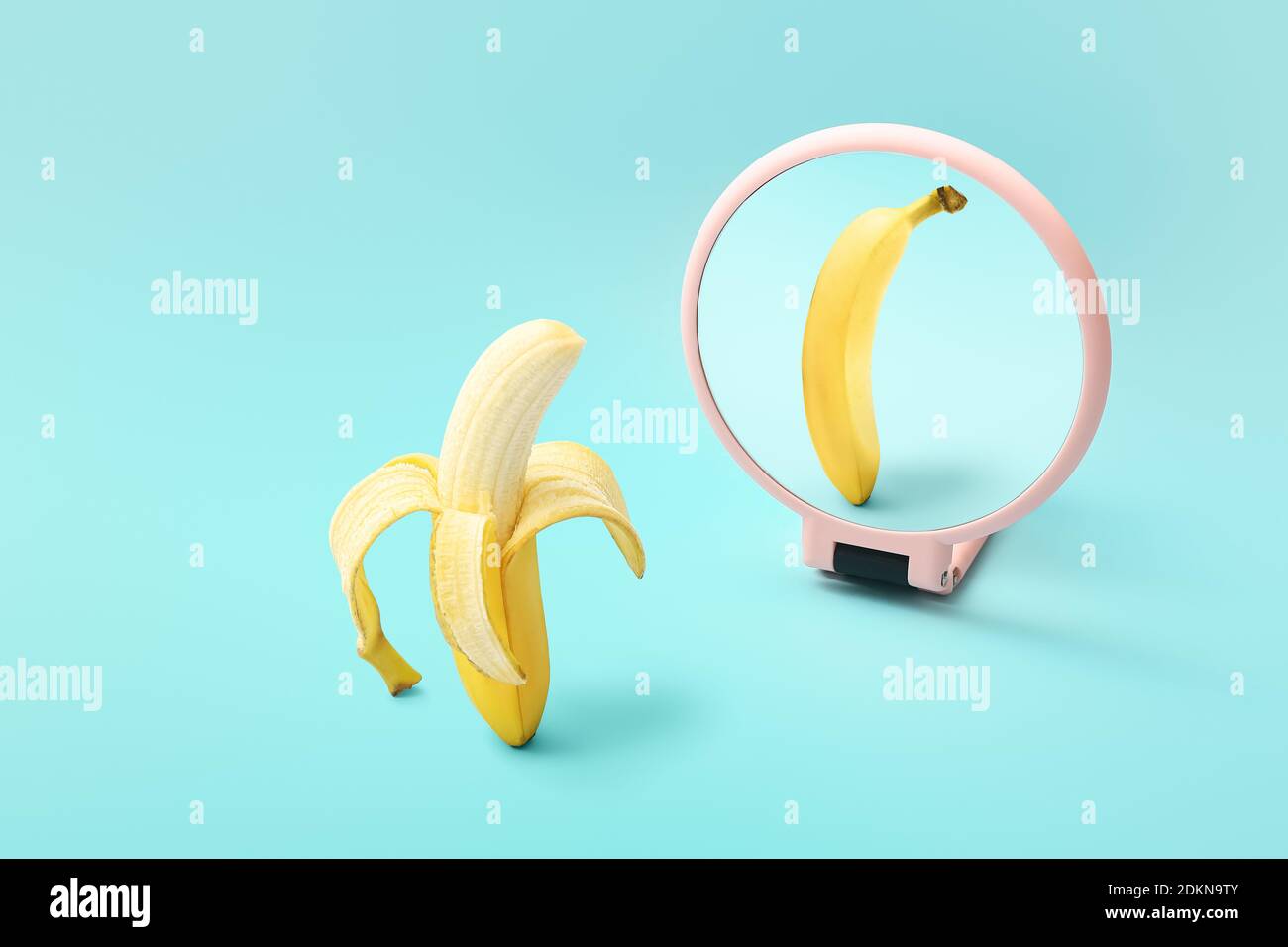Banana looking at its reflection in mirror on color background Stock ...