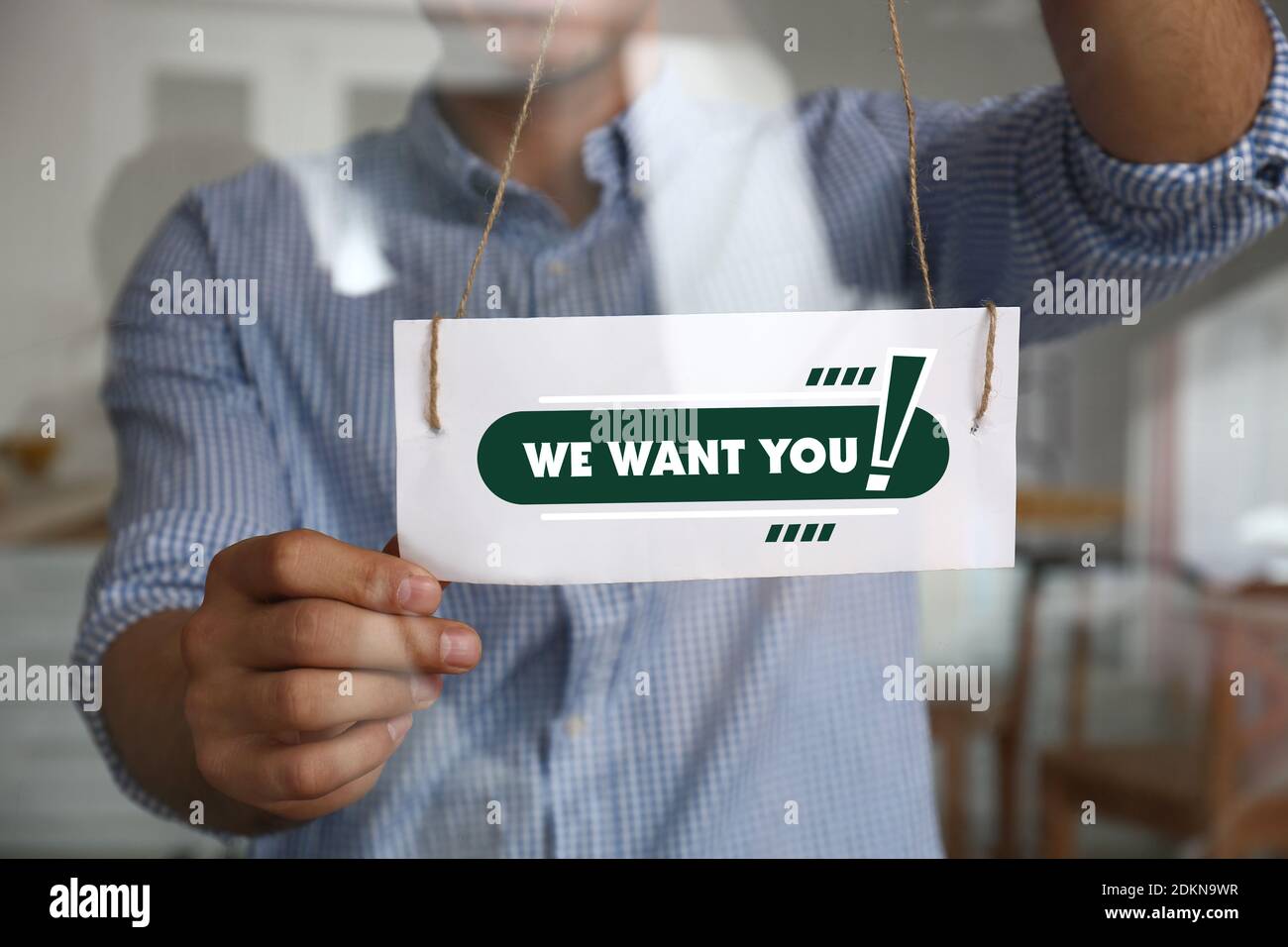 Young man holding sign board with text WE WANT YOU indoors. Concept of ...