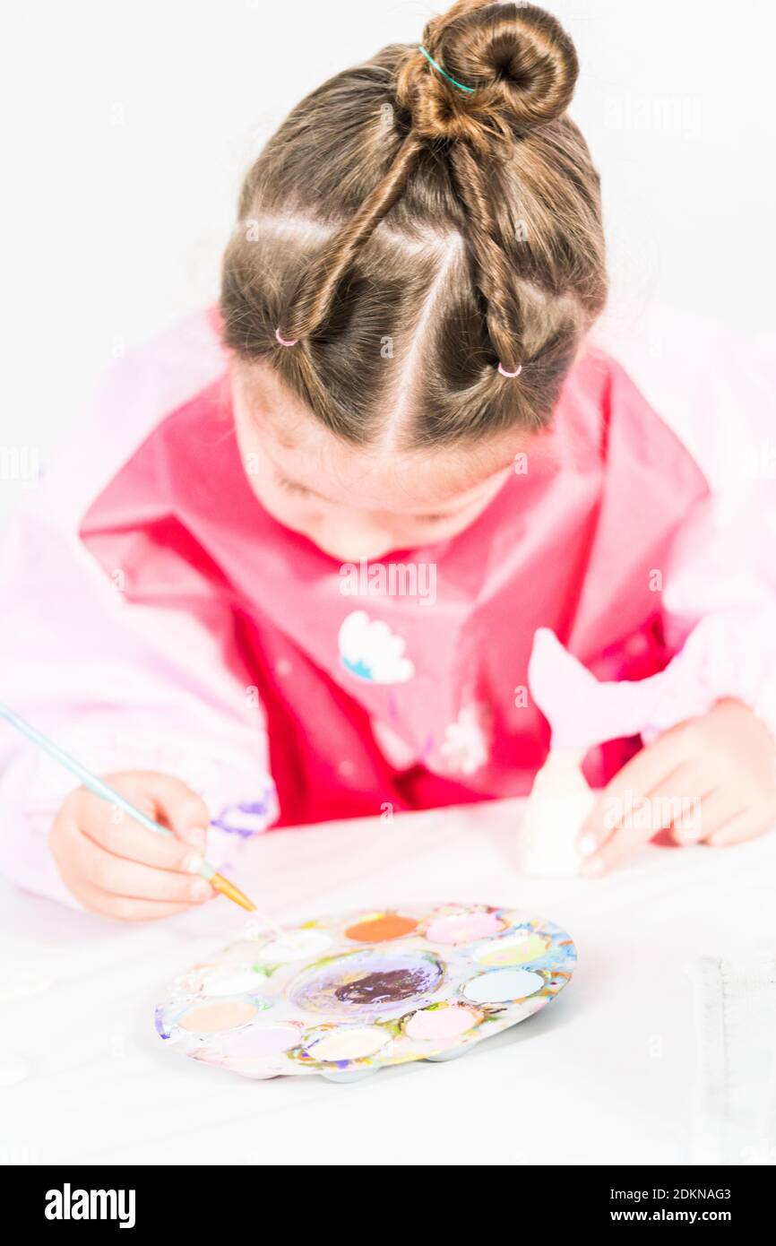Little girl painting mermaid tails made out of modeling clay with ...