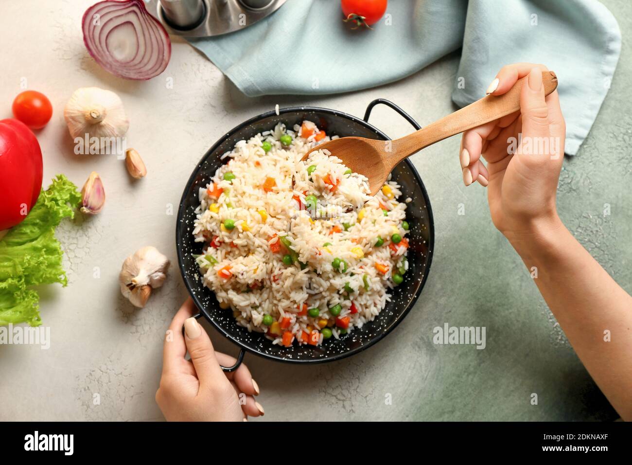 Female hands with tasty pilaf and wooden spoon on color background ...