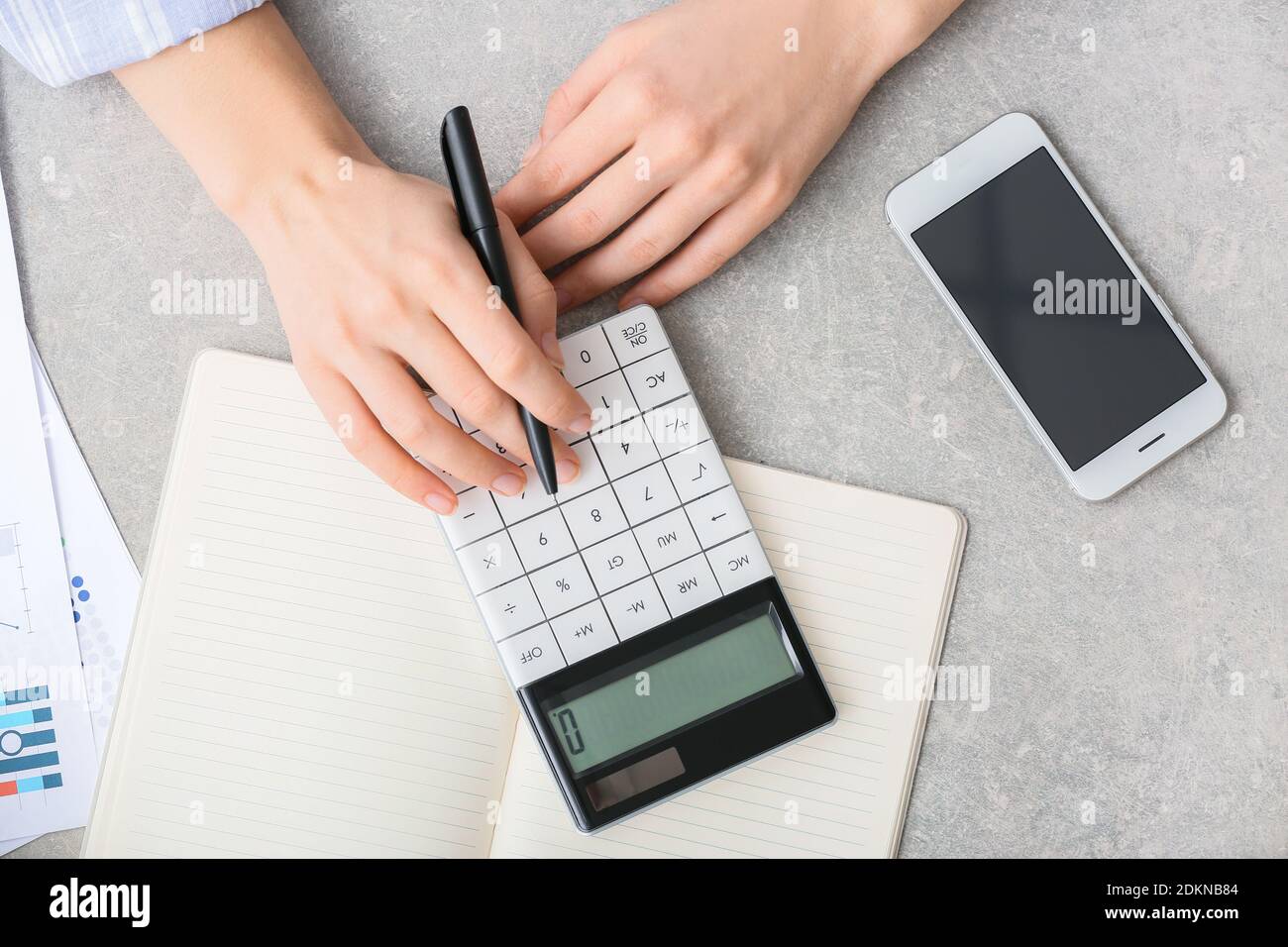 Female accountant with calculator and mobile phone working in office ...