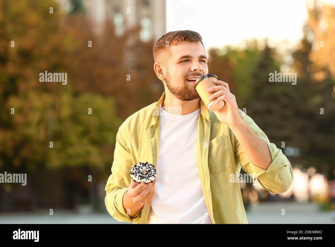 Handsome young man with sweet donut and coffee outdoors Stock Photo - Alamy