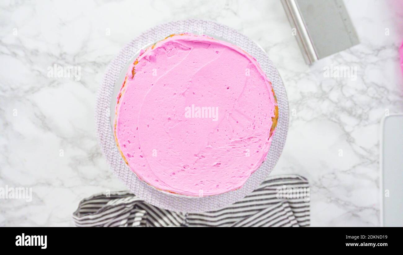 Flat lay. Step by step. Frosting round funfetti cake layers with pink ...