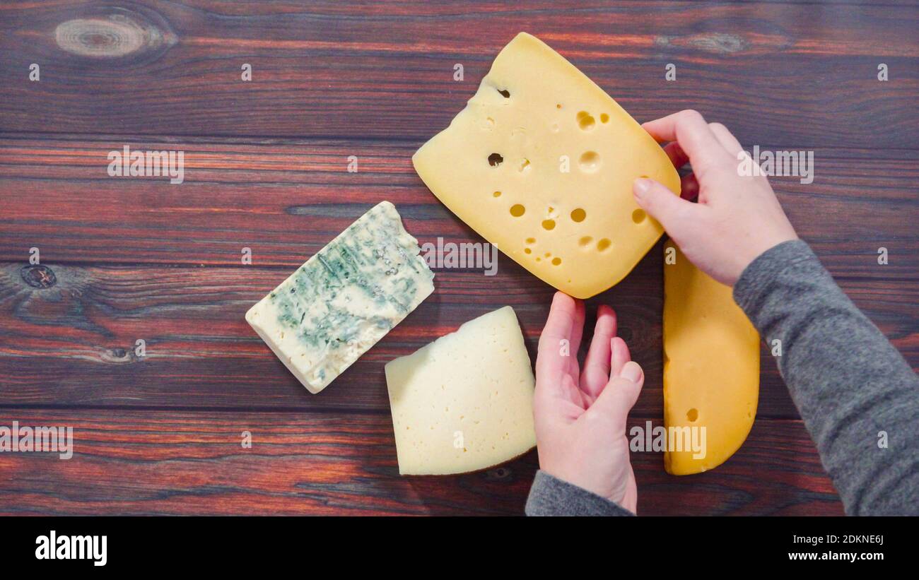 Flat lay. Large wedges of gourmet cheese on a rustic wood background ...