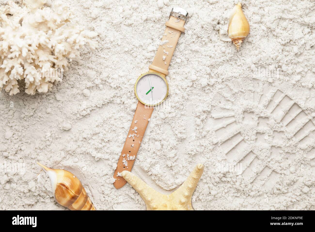 Wrist watch with sea shells on beach sand Stock Photo - Alamy
