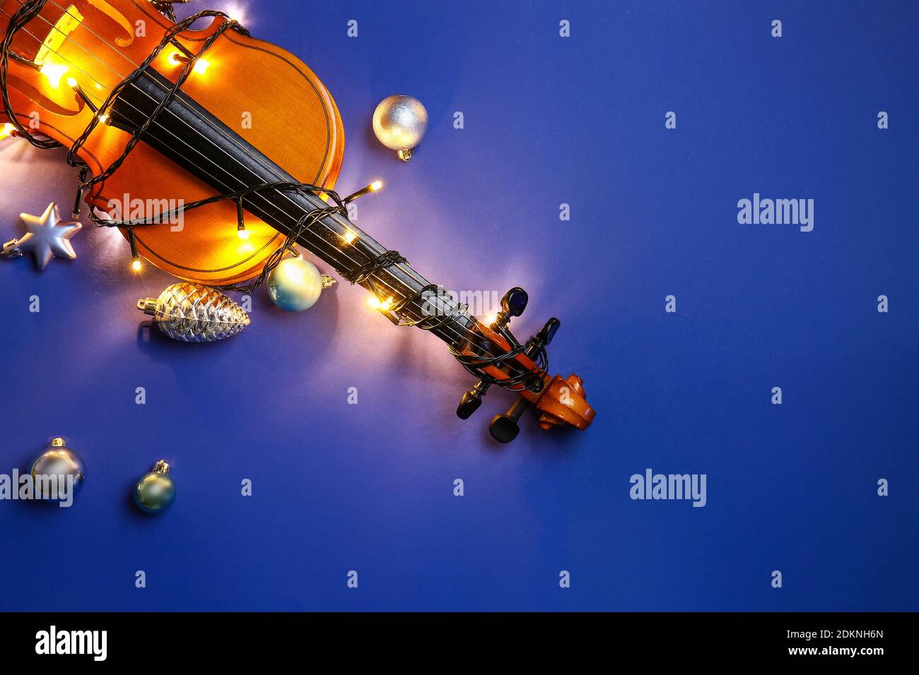 Violin with Christmas lights and decor on color background Stock Photo ...