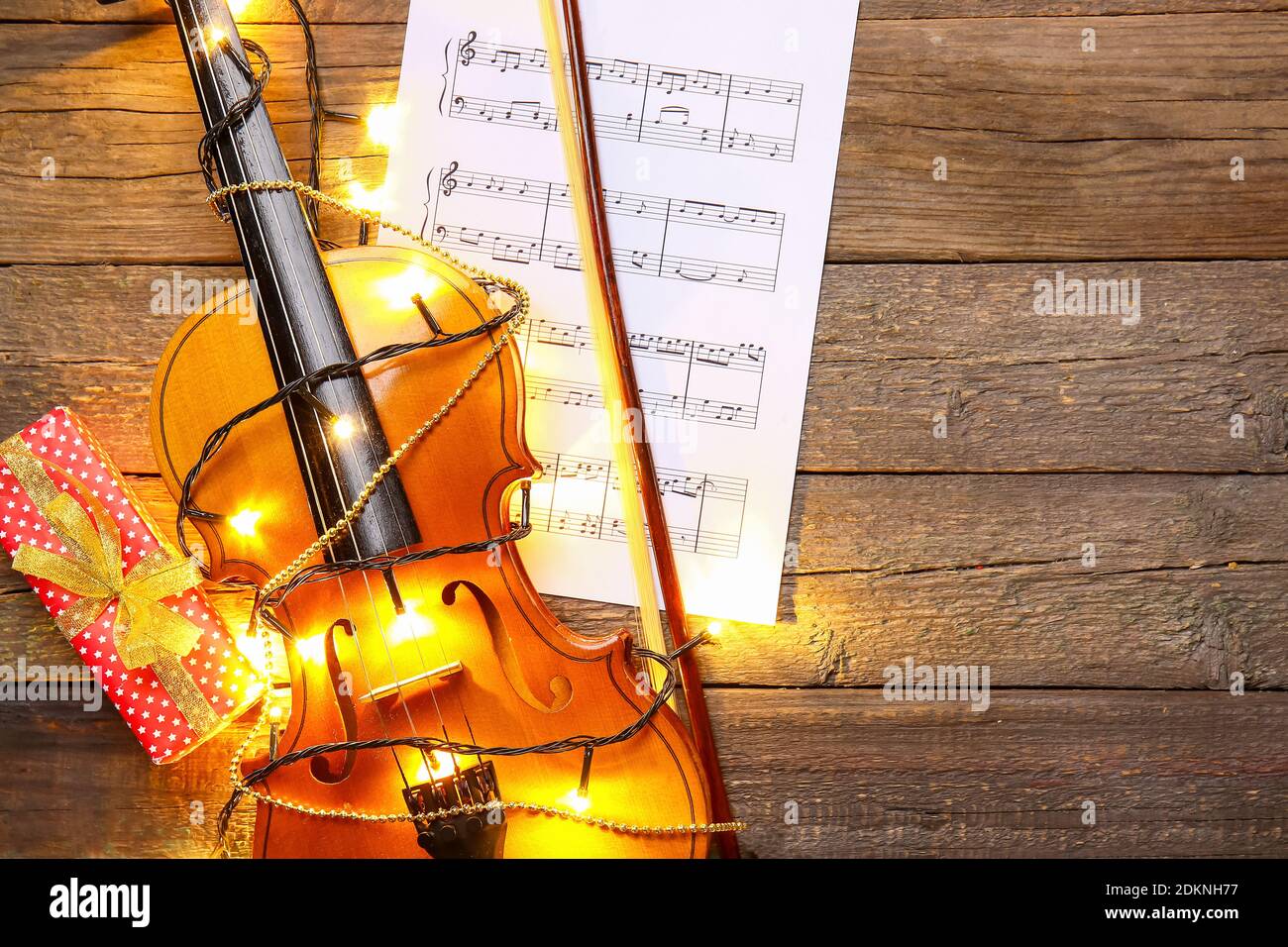 Violin with Christmas lights and music notes on wooden background Stock ...