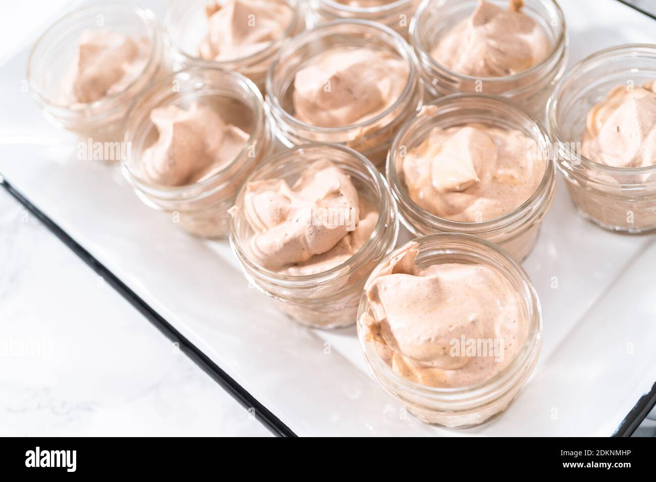 Scooping mixture into the small glass jars to make homemade chocolate ...