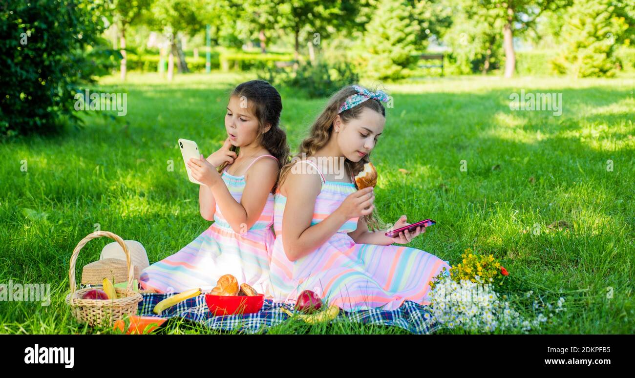 Little kids look at mobile phones suffering smartphone addiction at family summer picnic ...