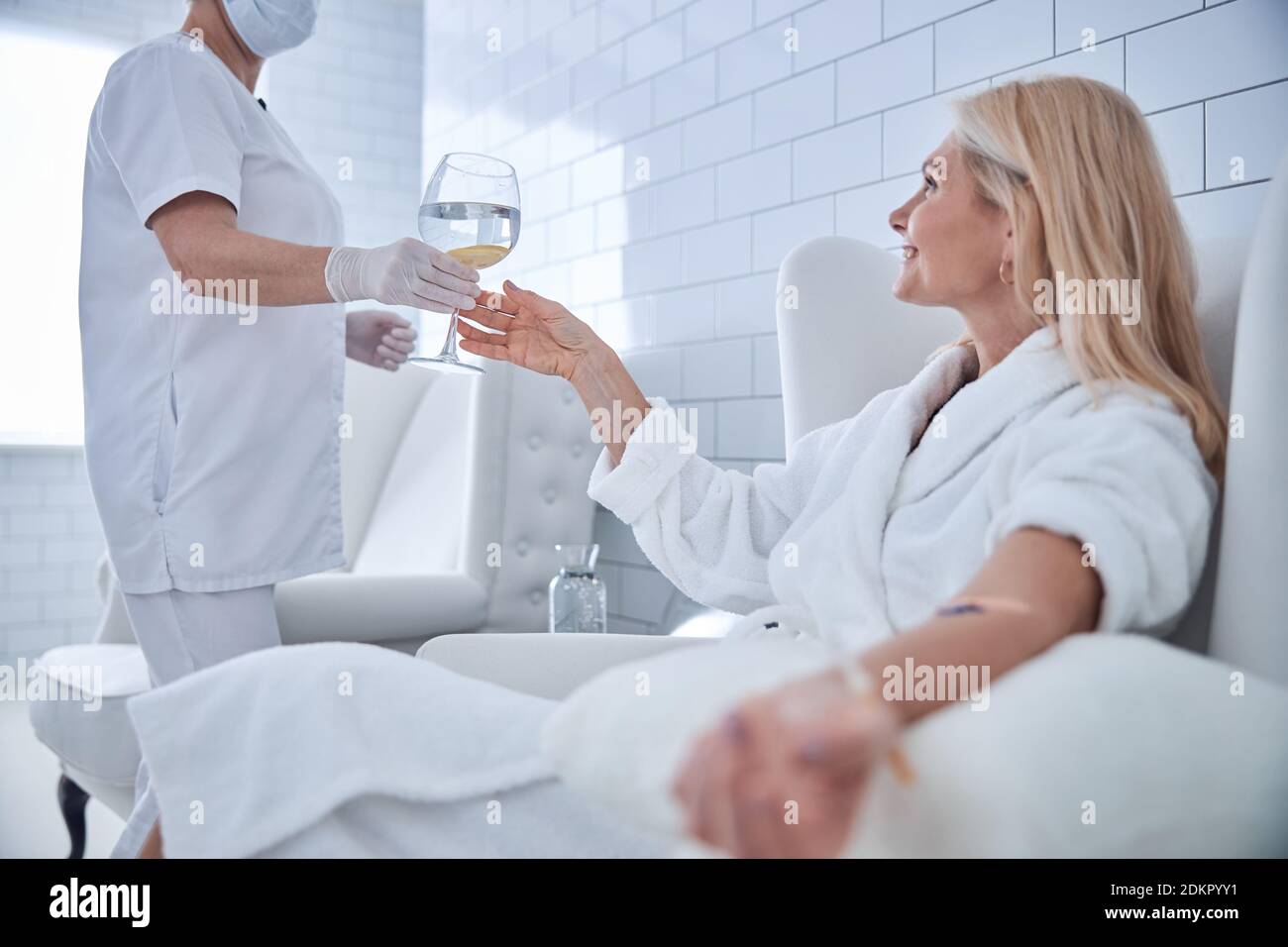Female doctor getting glass of water to elegant patient in beauty ...