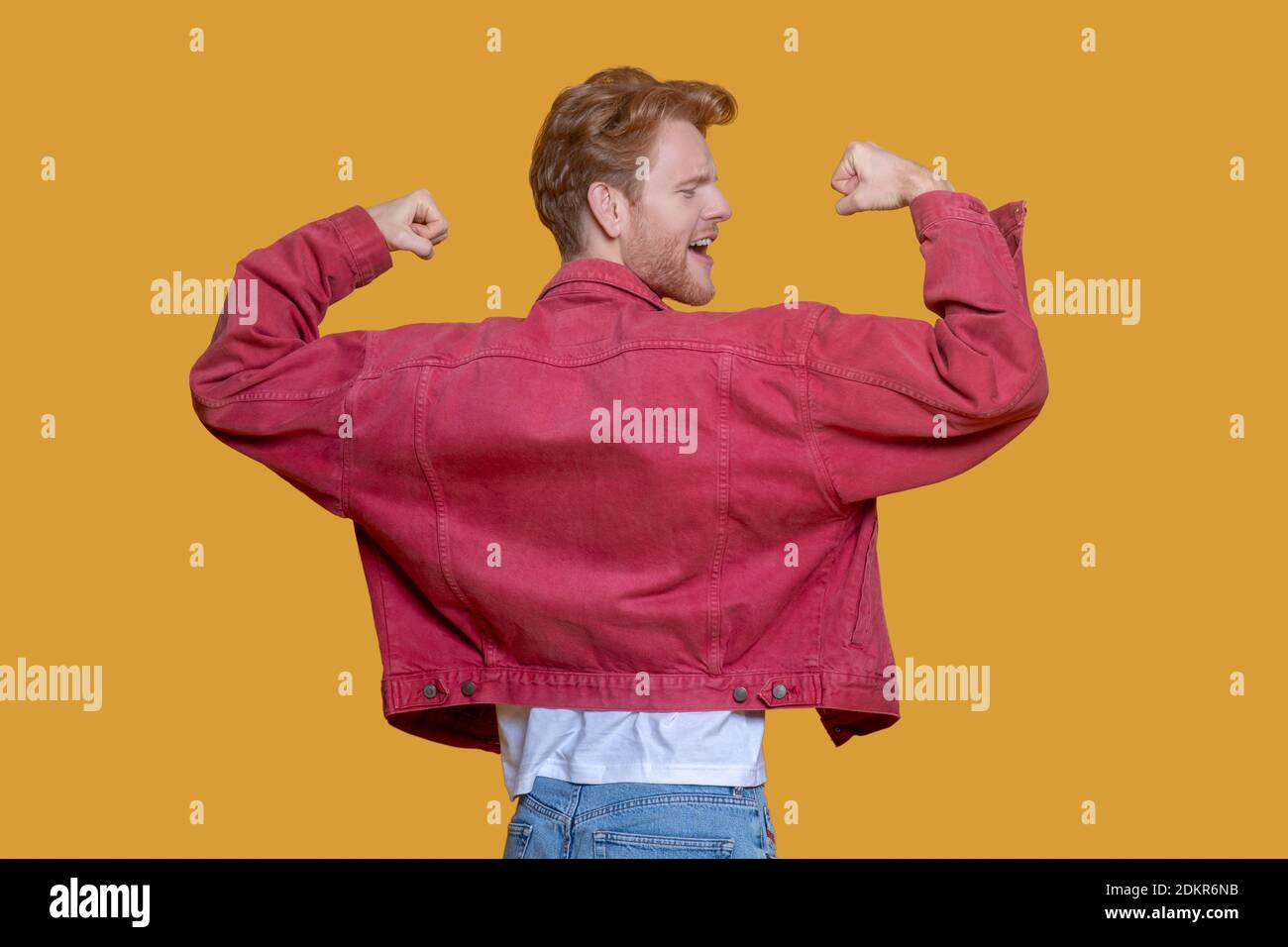Red-haired bearded young man in red jacket showing muscles Stock Photo ...