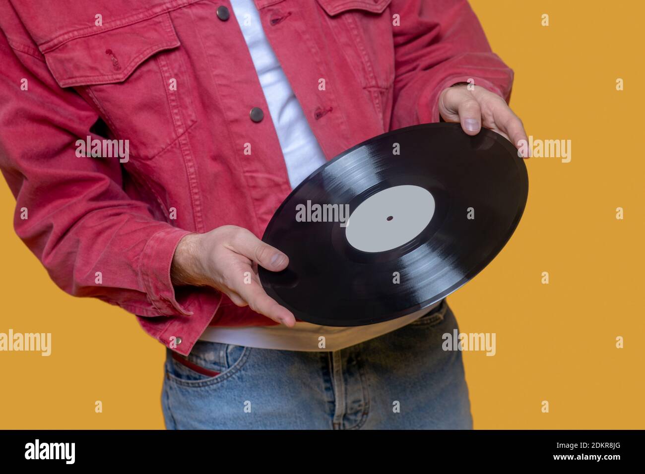 Man in red jacket holding a record in hand Stock Photo - Alamy