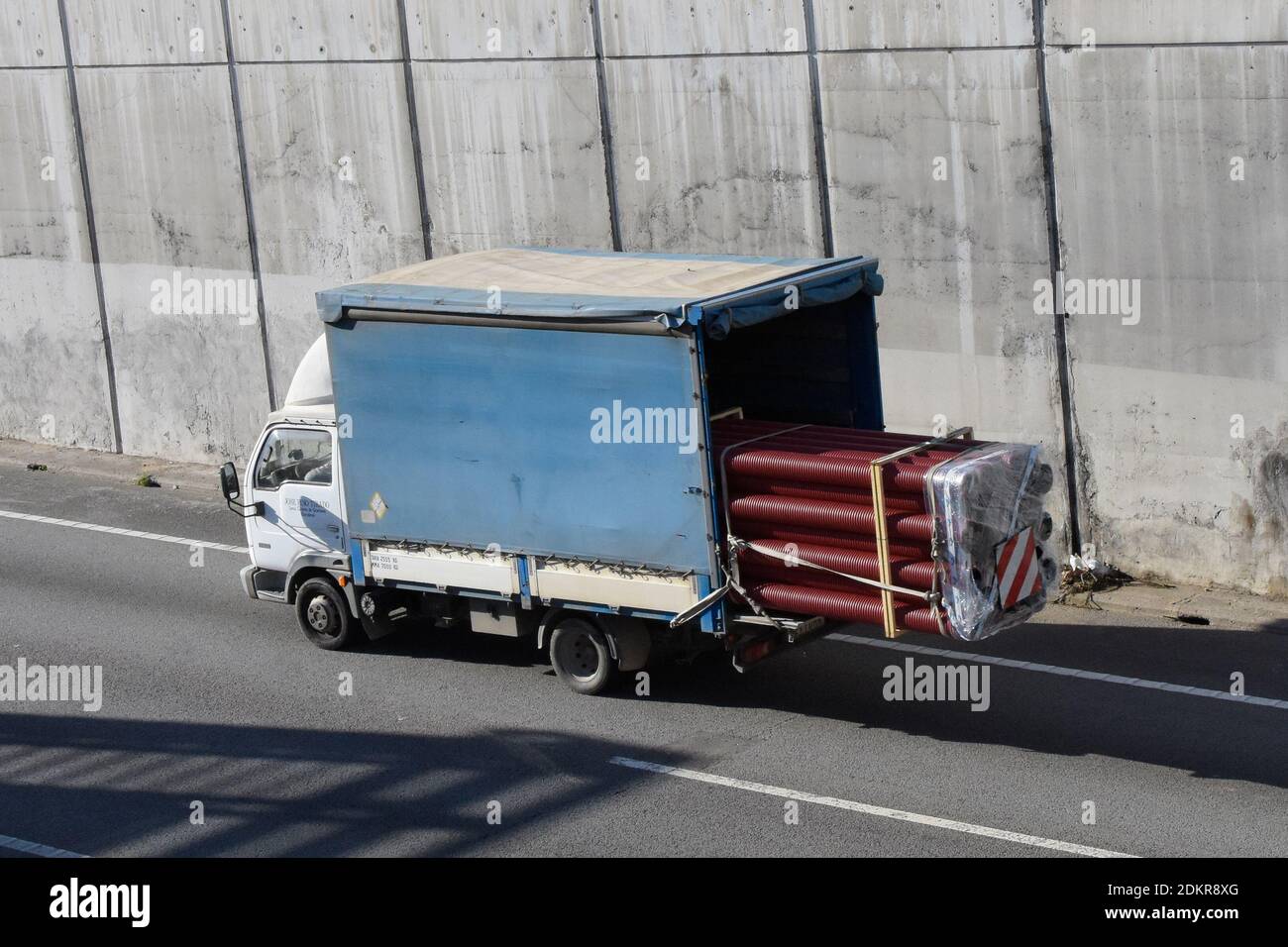 Blue truck transporting red plastic tubes for underground protection ...