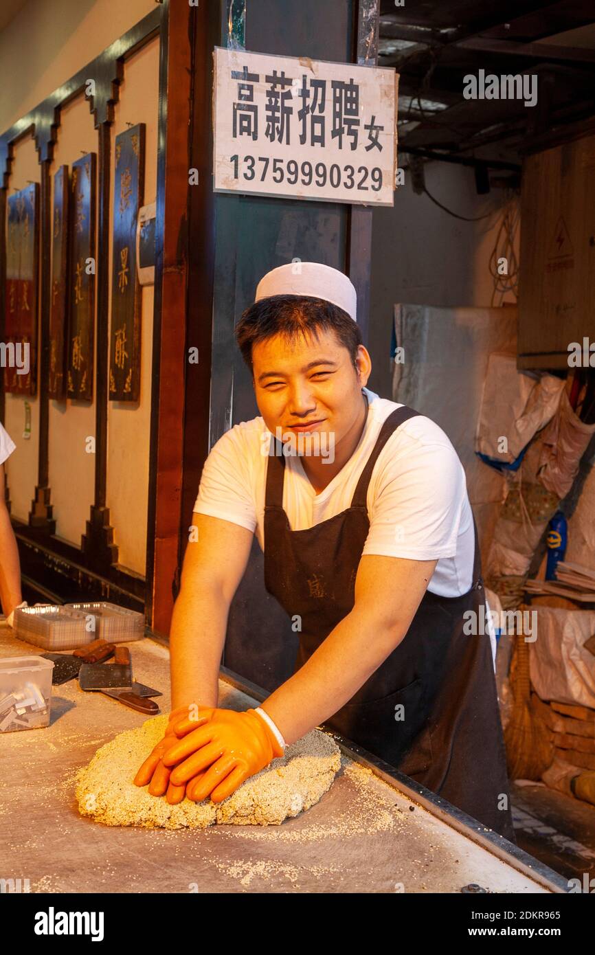 Chinese man kneading bread at street food vendor in Muslim Quarter Xian ...