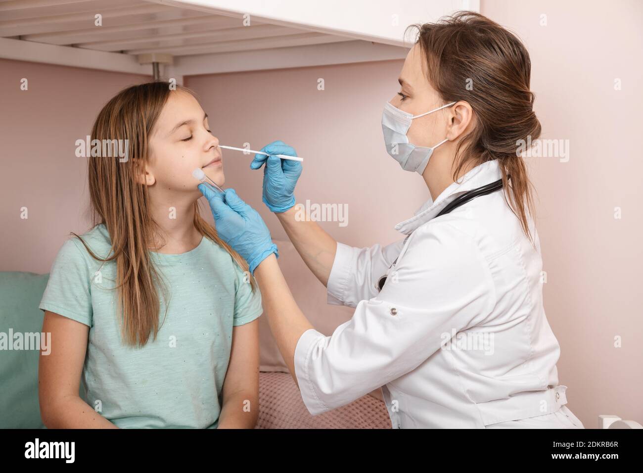 Pediatrician taking nasal mucus test sample from elementary age girl's ...
