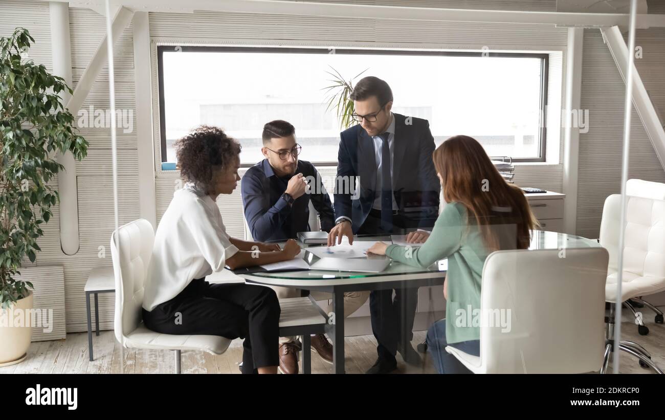 Multiracial colleagues gather in office boardroom discussing paperwork ...