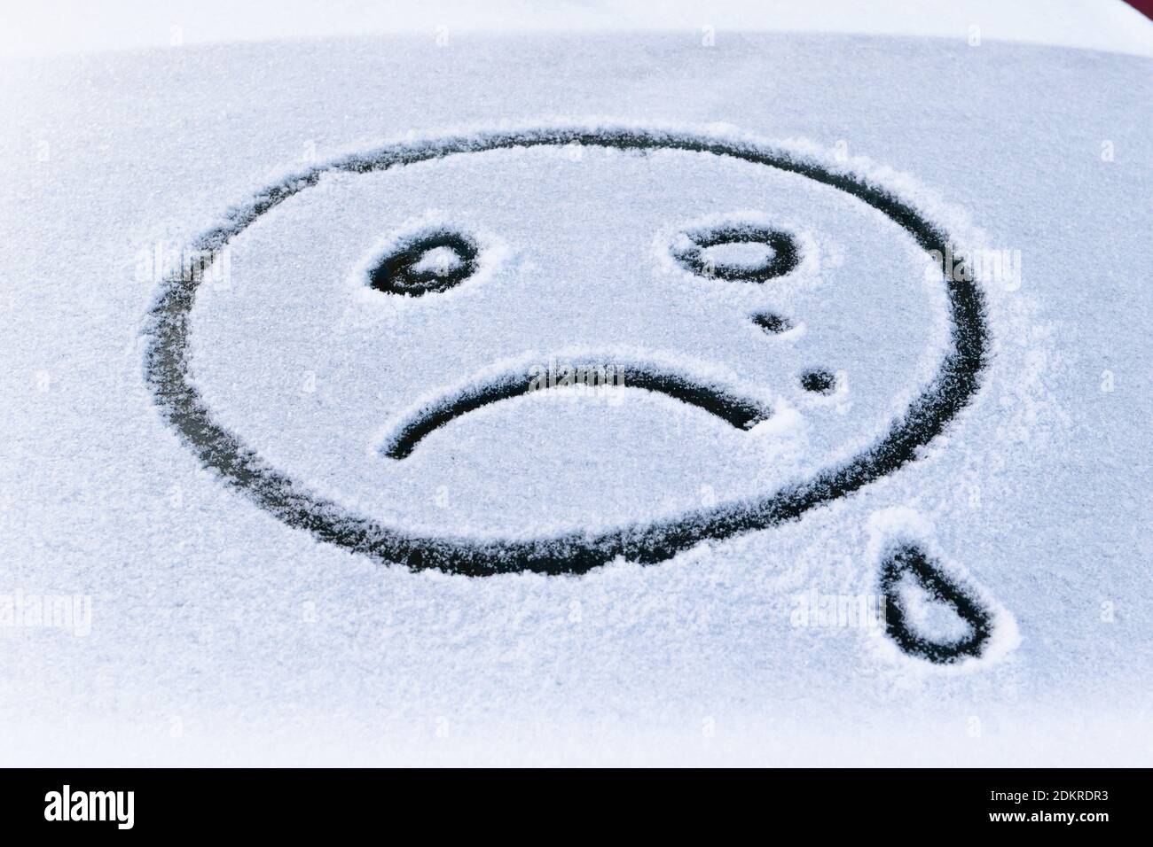 image of a crying face emoji on the snow on the back window of a car on ...