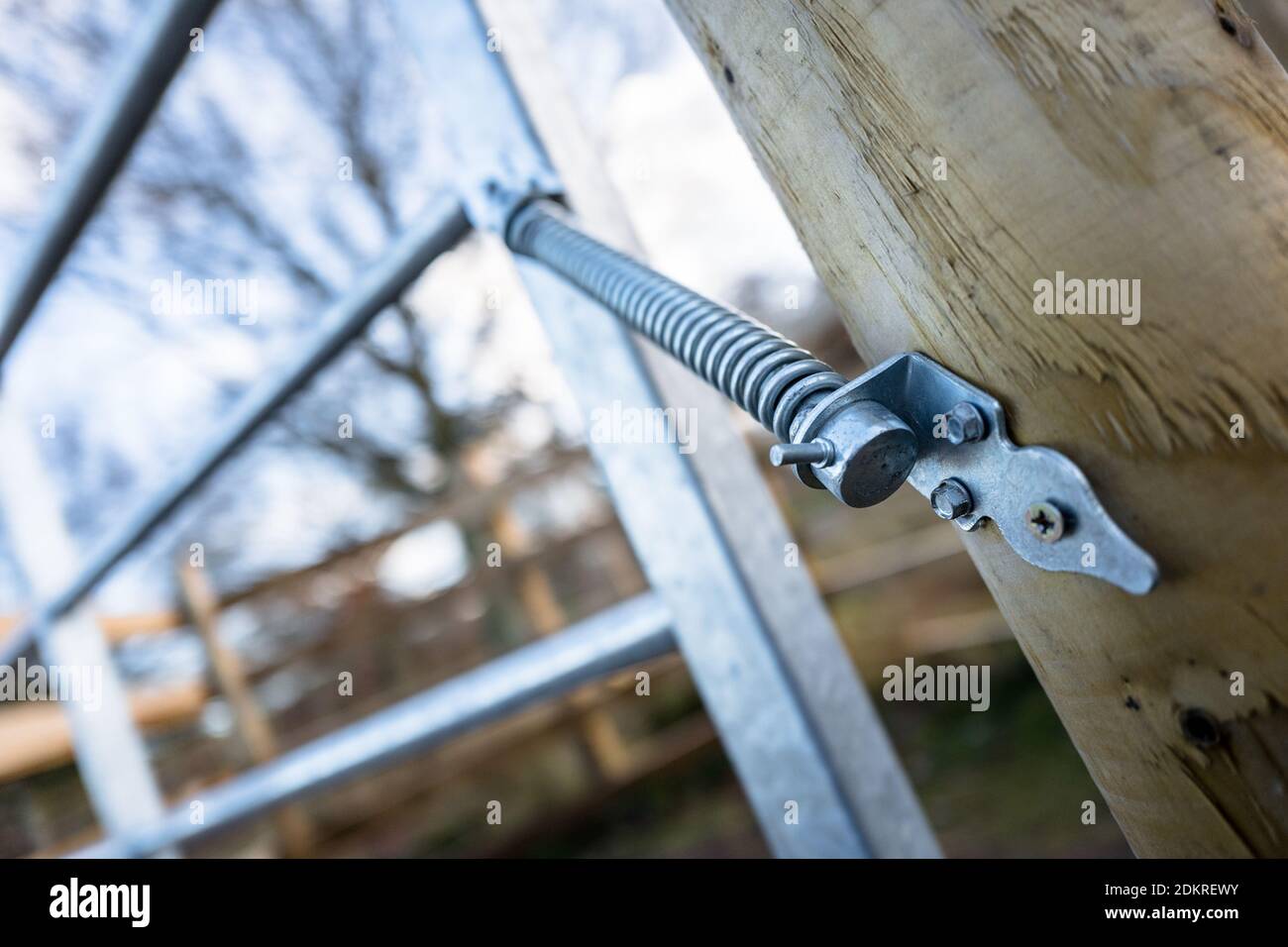 Spring loaded galvanised metal gate attached to a wooden post Stock ...
