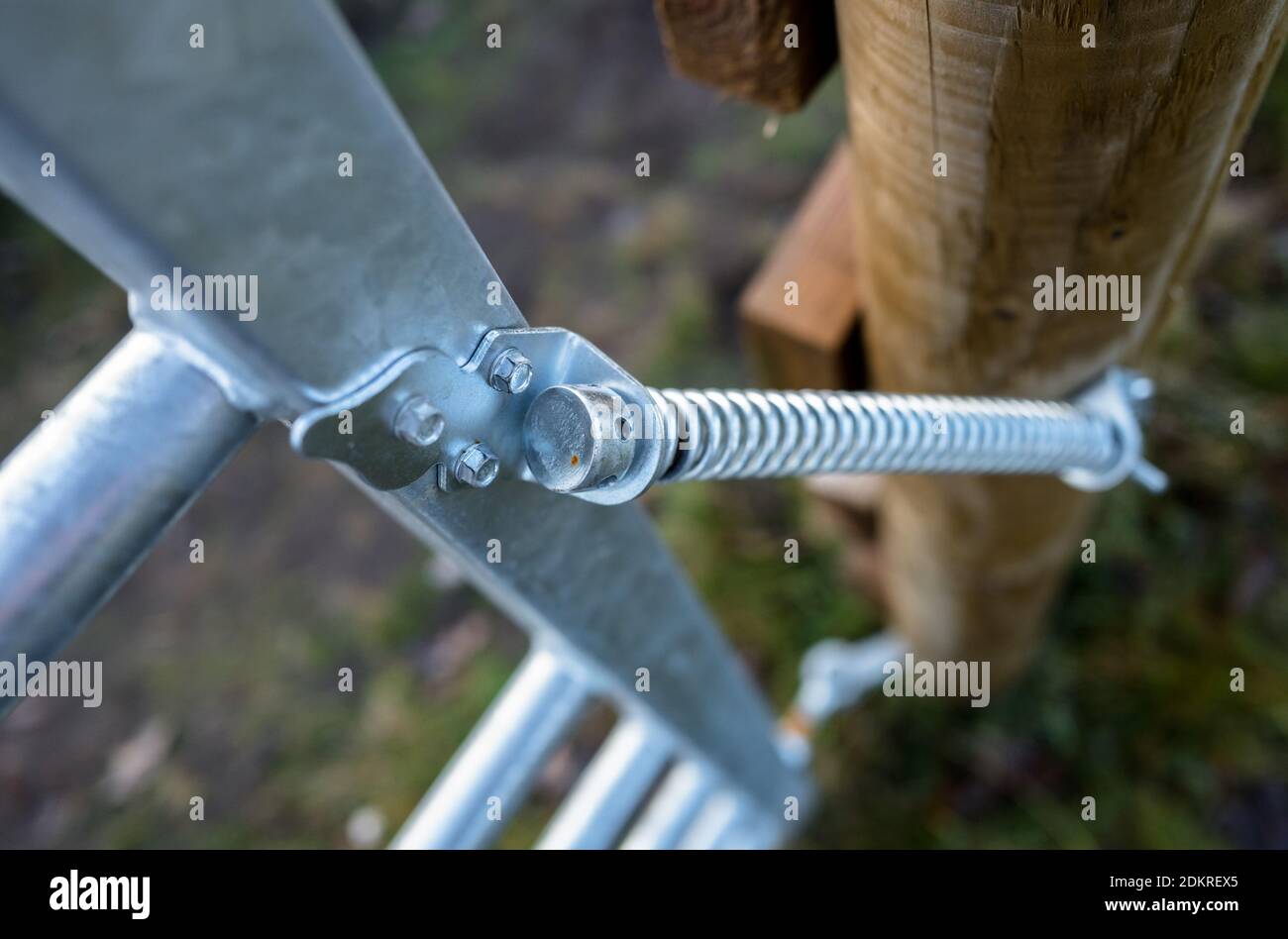 Spring loaded galvanised metal gate attached to a wooden post Stock ...