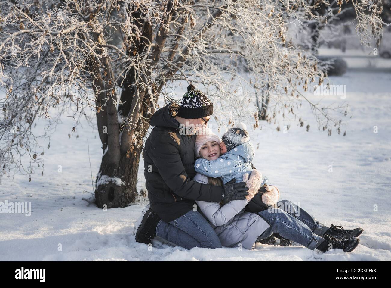 Happy family hugging together near tree in winter park Stock Photo - Alamy
