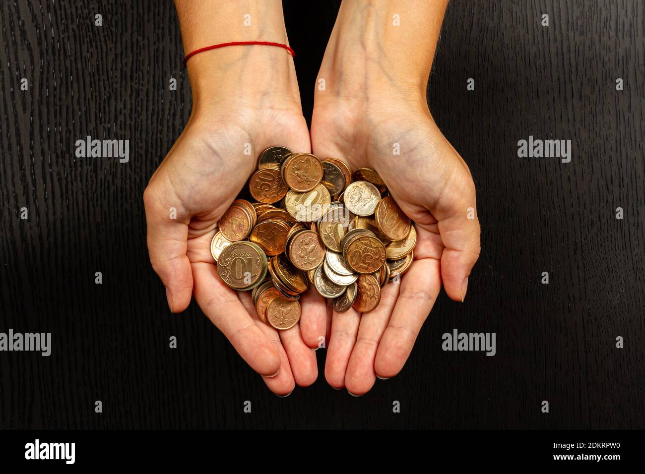 girl holding a handful of coins in her hands on a black table ...