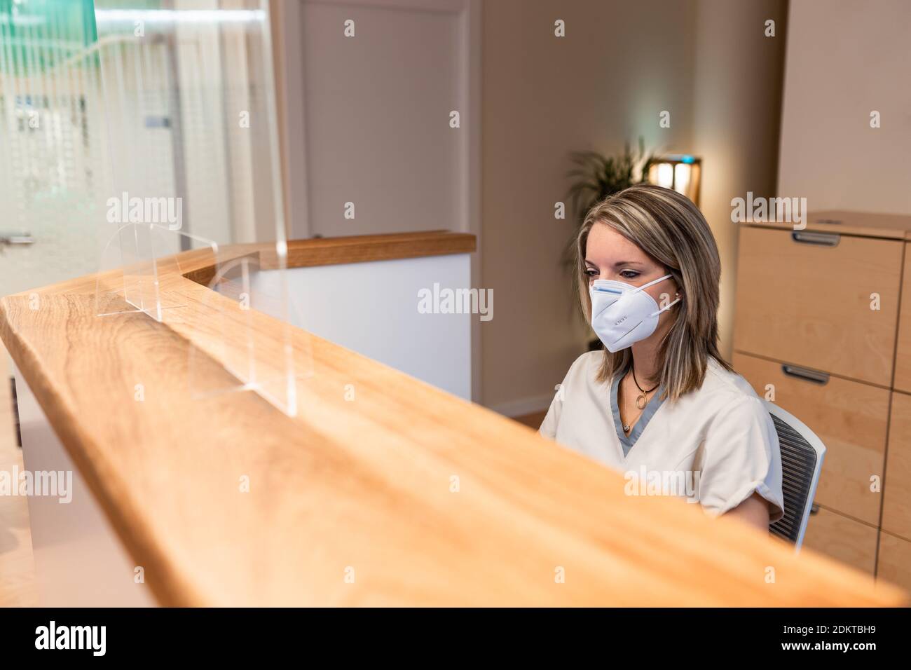 female receptionist from a physiotherapy center behind a reception desk ...