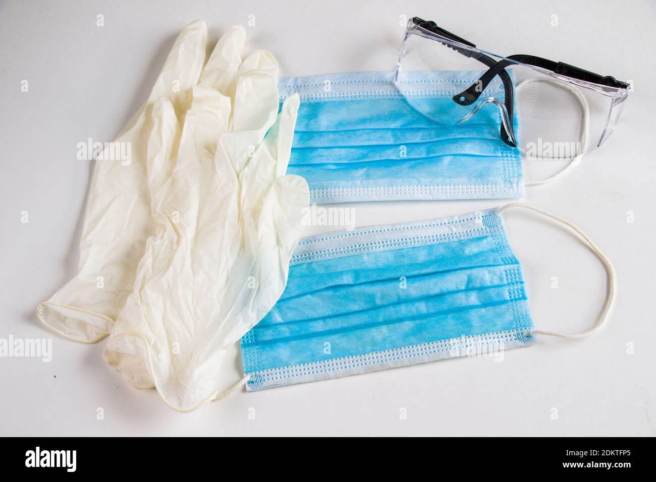 Medical gloves, face masks and safety glasses on the white background ...