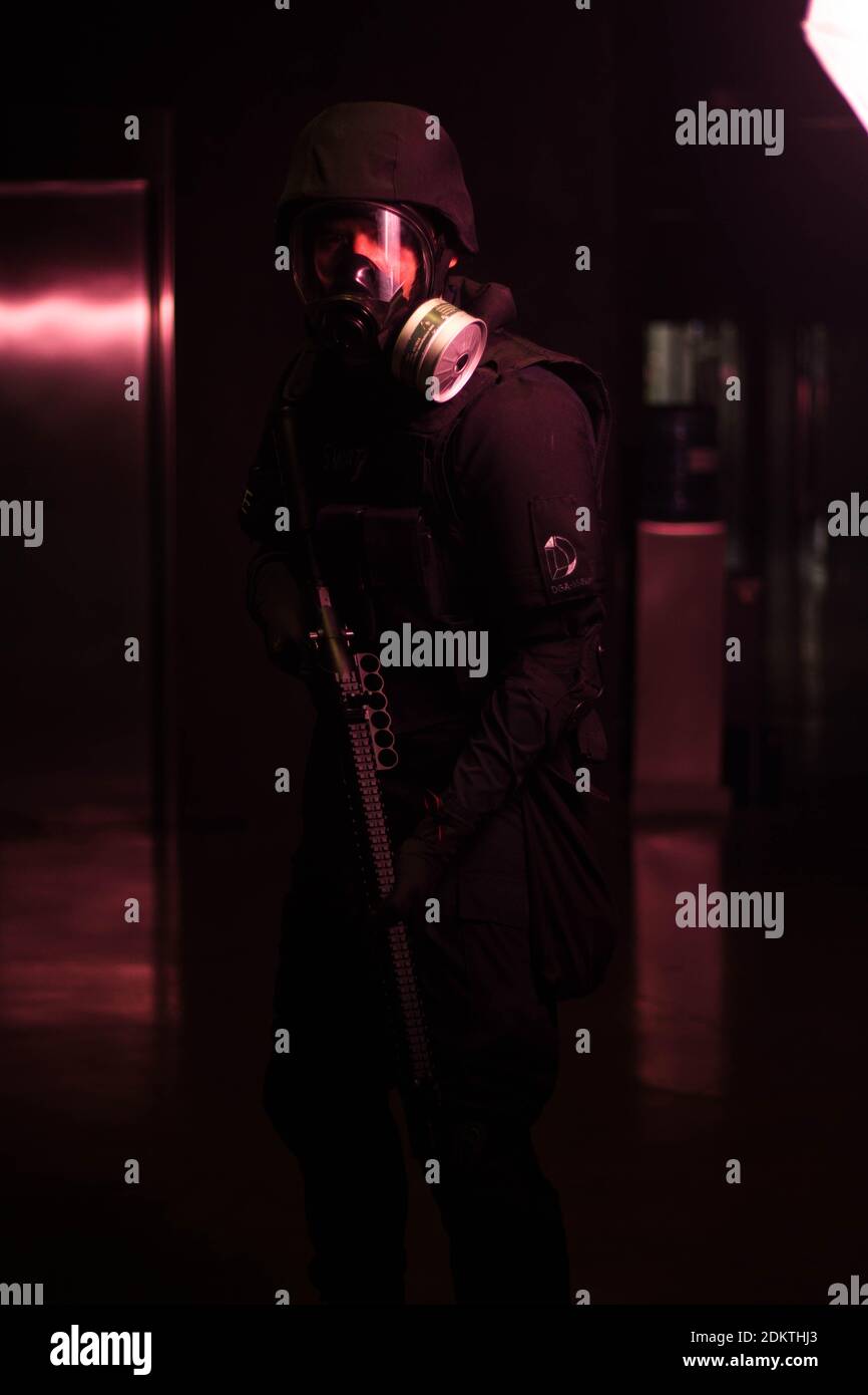 Portrait Of Police Man Holding Gun While Wearing Gas Mask At Night ...