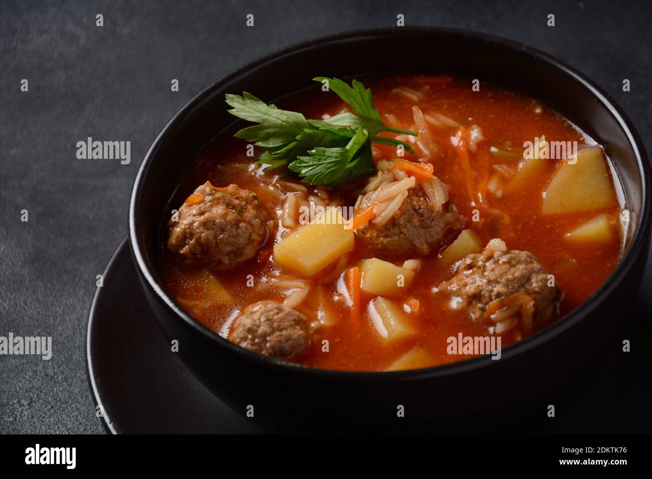 Patatesli Sulu Kofte - Turkish soup with meatballs in black bowl Stock ...