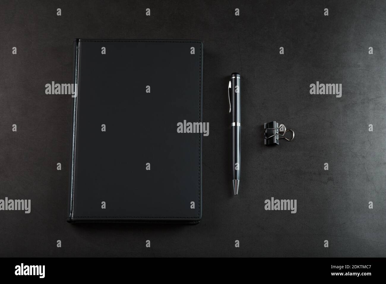 Black Notepad with a black pen on a black background. Top view ...