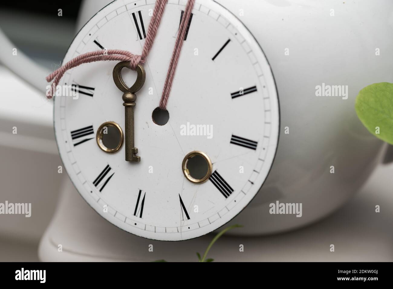 Old removed clock face with roman digits haning on white teapot with ...