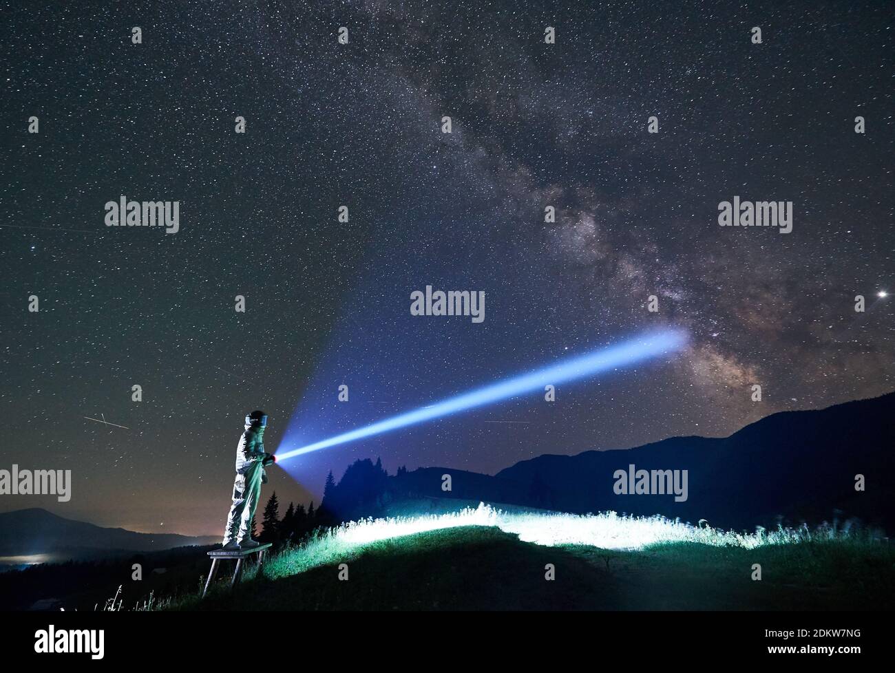 Spaceman astronaut illuminating beautiful starry sky with flashlight at ...