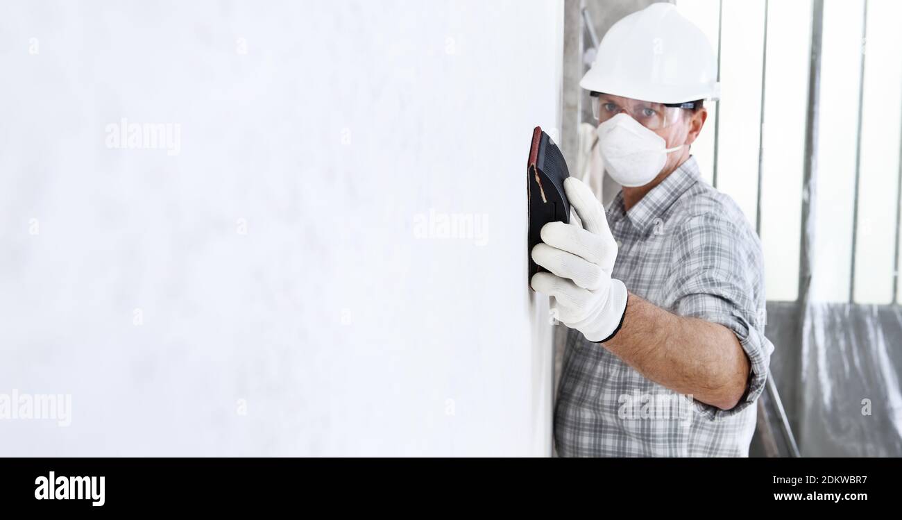 man sand the wall with sandpaper, professional construction worker with ...