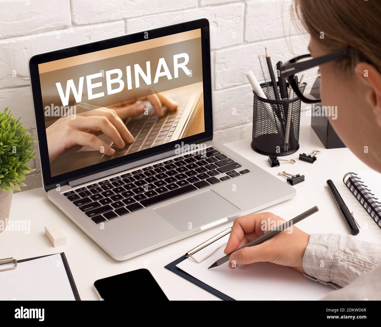 Young woman office worker taking notes while listening to webinar Stock ...