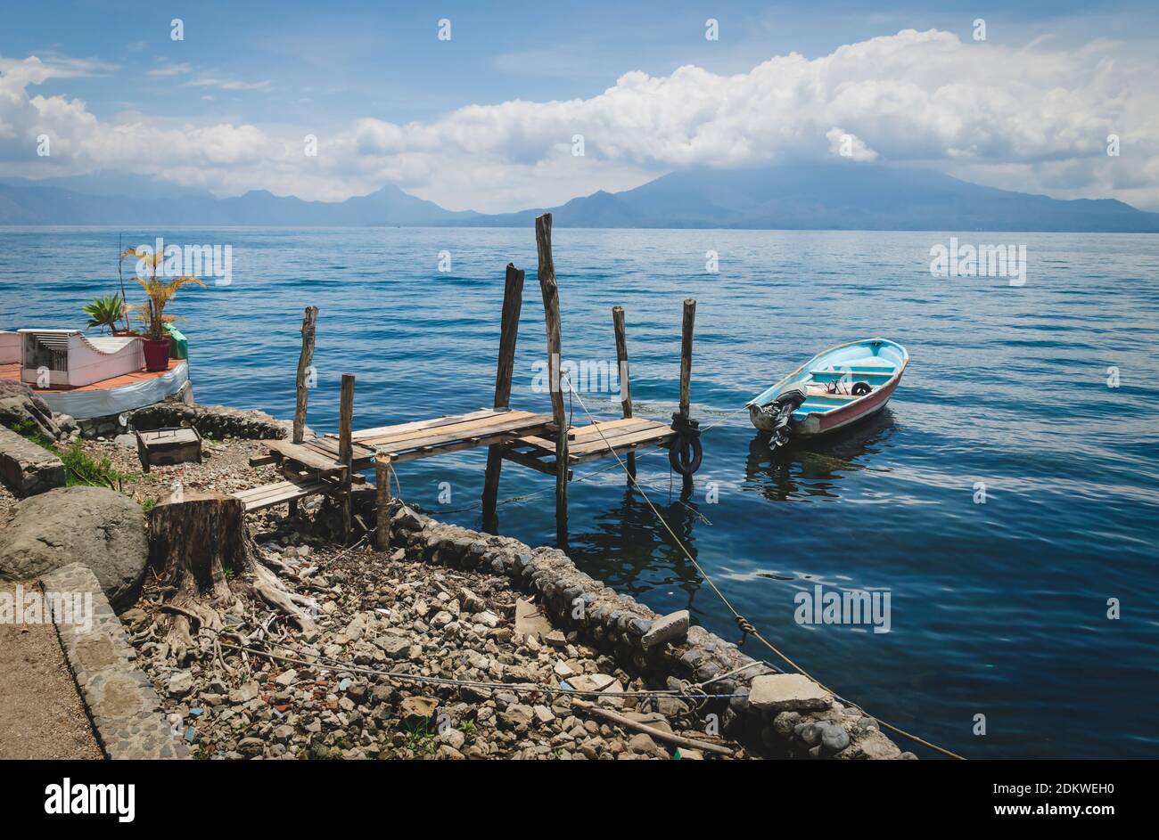 Wooden seat at jetty with boat along lake Atitlan at the coast of Santa ...