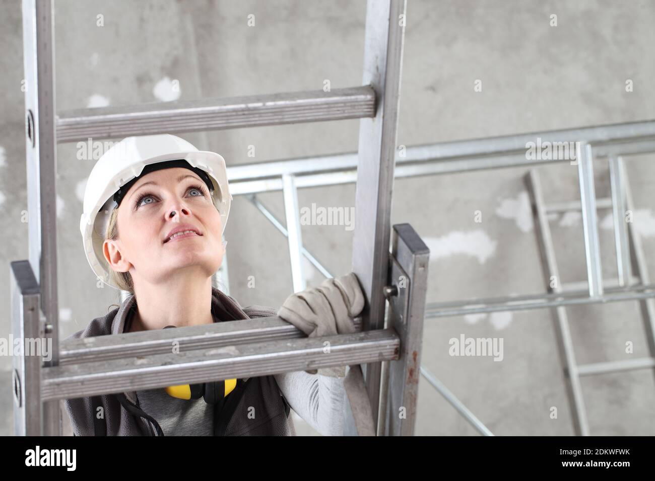 woman construction worker builder on ladder wearing white helmet and ...