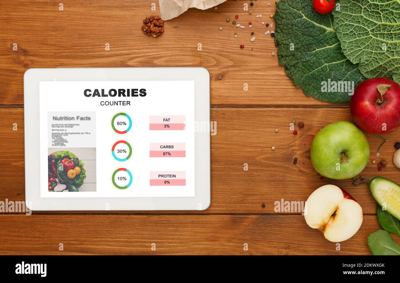 Digital tablet with calories counter app laying next to fruits and ...