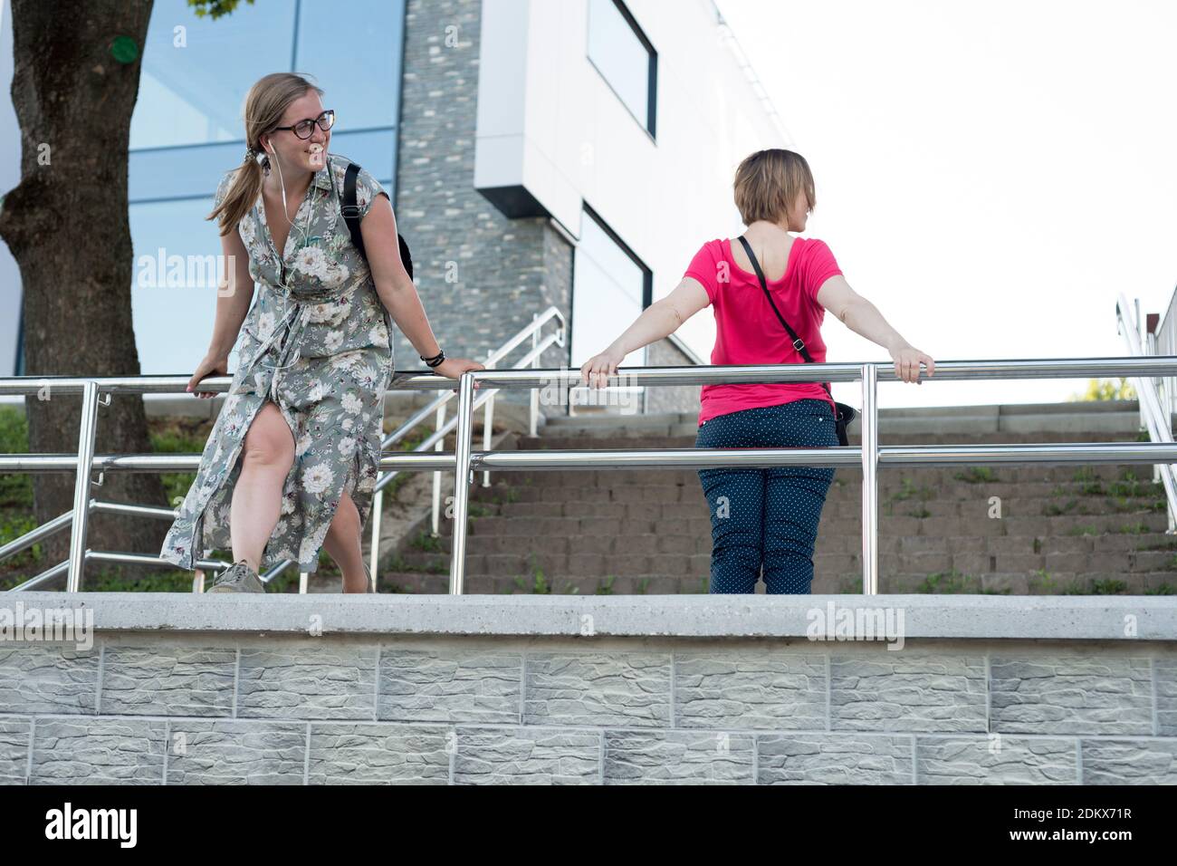Two funny women with headphones are walking on the street Stock Photo ...