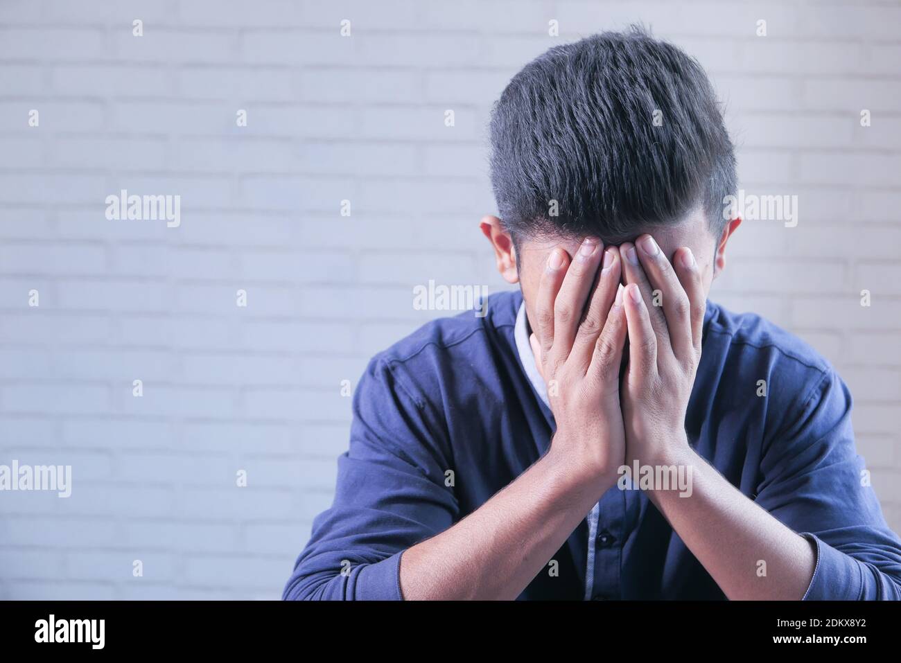 sad man in hood cover face with hands isolated in black Stock Photo - Alamy