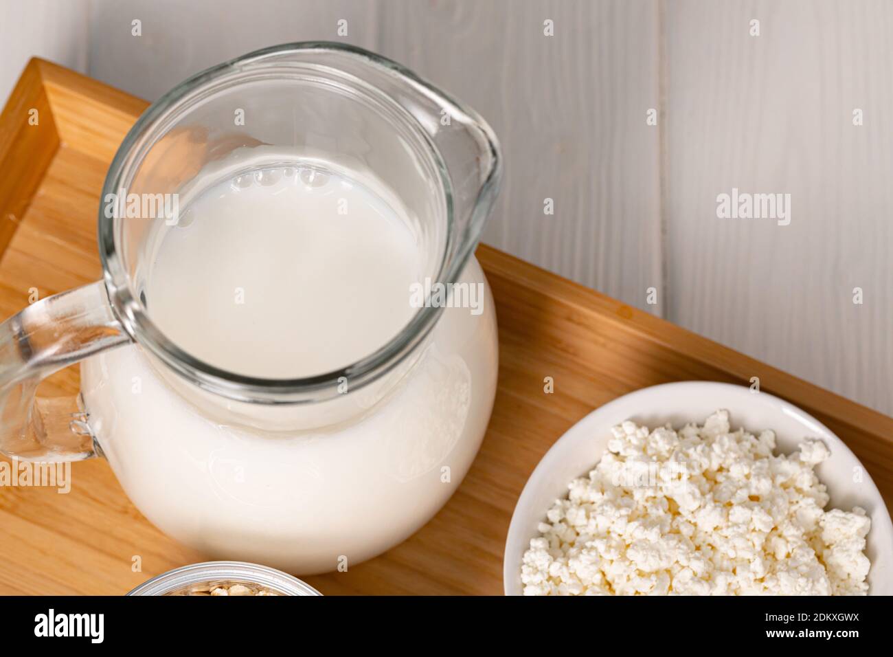 Glass pitcher of milk and bowl of cottage cheese on wooden table Stock ...