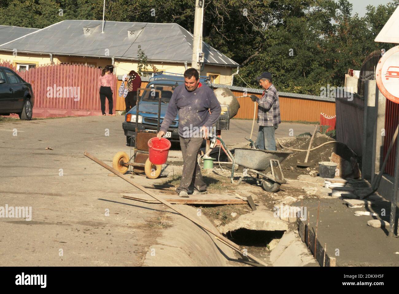 People in Romania's countryside poring out concrete for a new sidewalk ...