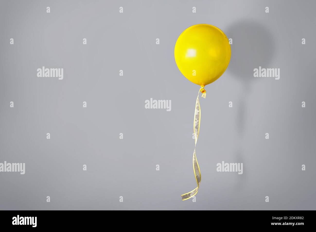 Yellow one balloon flying agains gray background Stock Photo - Alamy