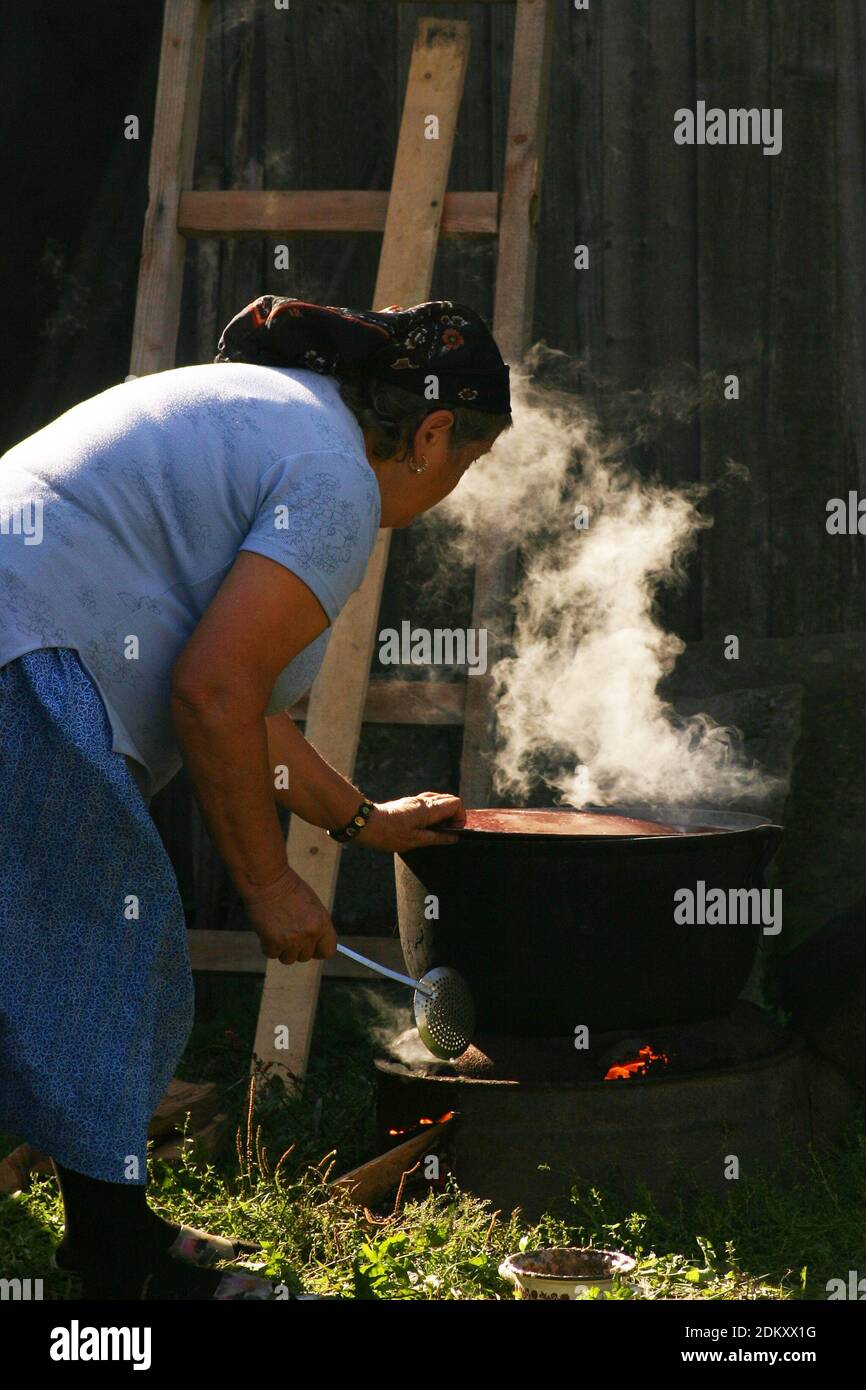 Vrancea County, Romania. Woman cooking outdoors in large cauldron over ...