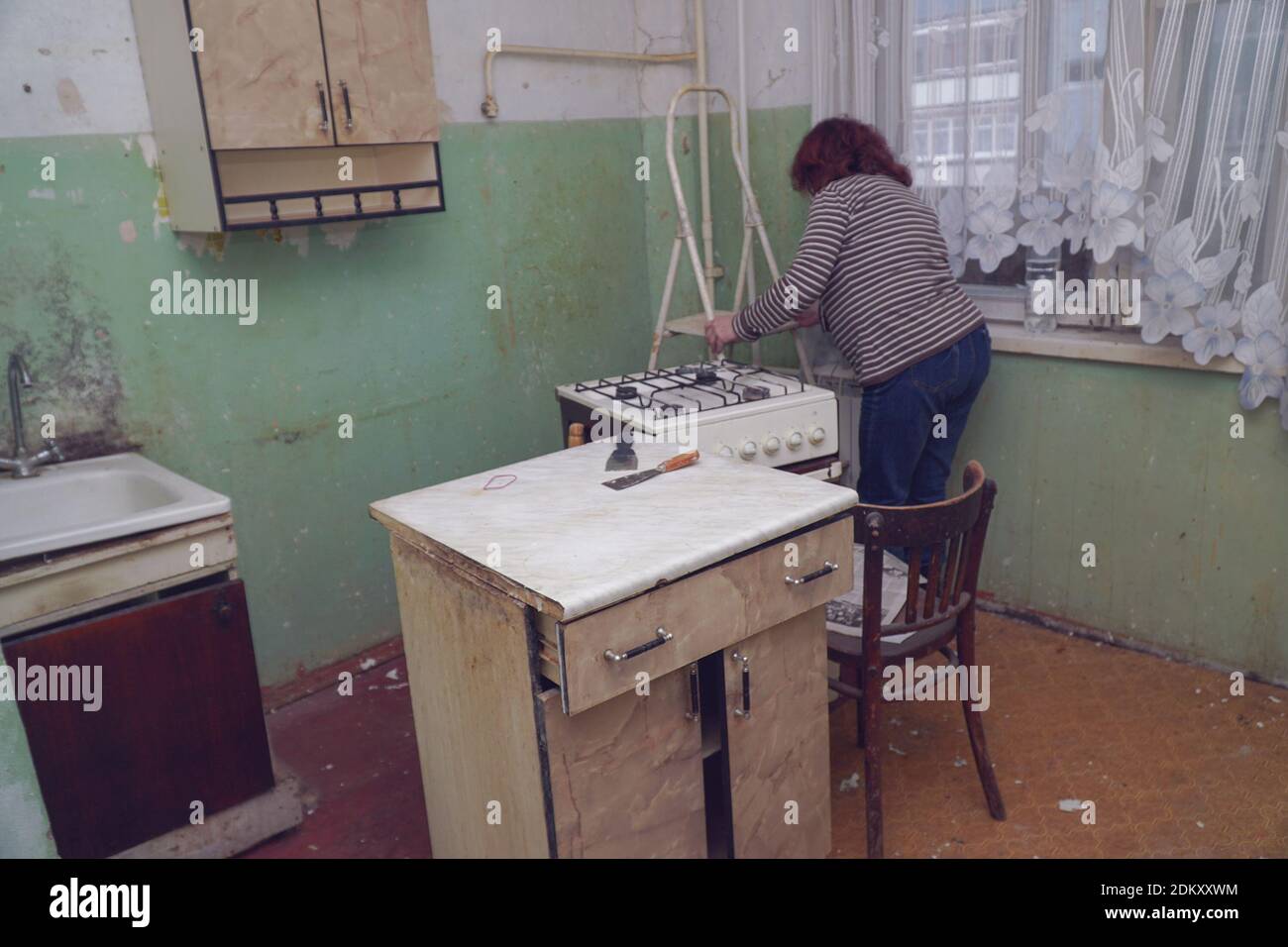 A woman prepares an old dirty kitchen for repair Stock Photo - Alamy